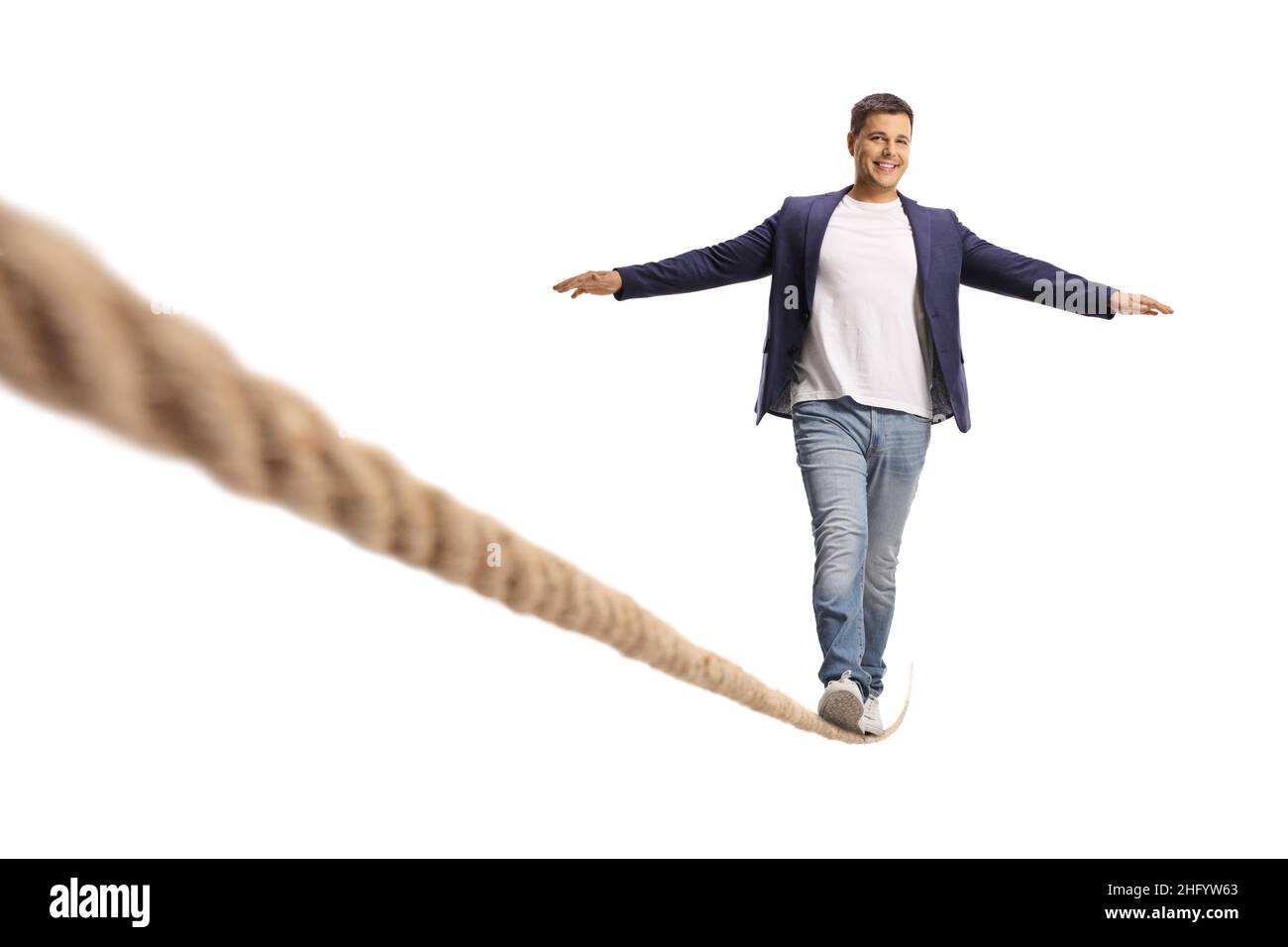 Full length portrait of a young man walking on a tightrope and smiling ...