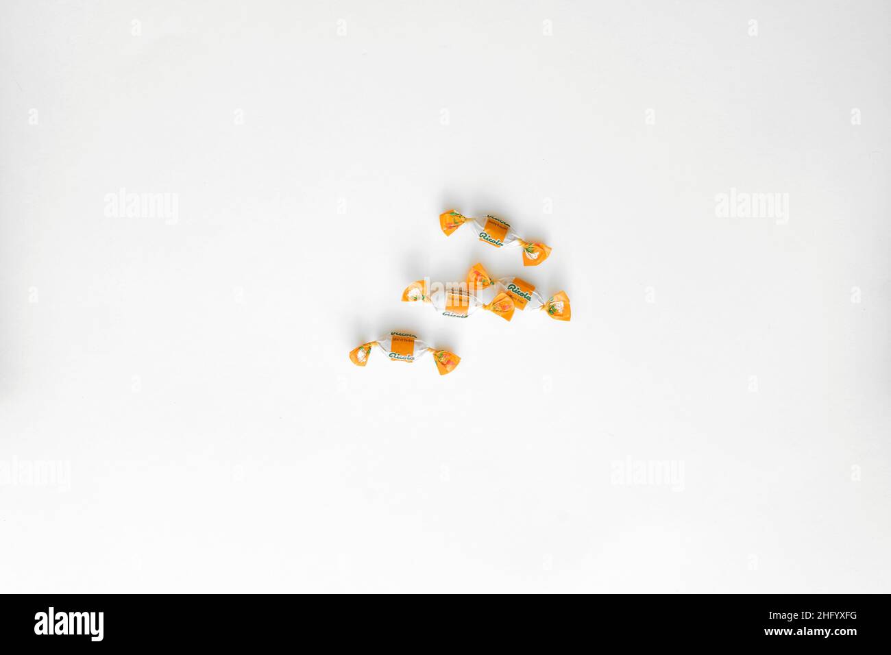 Four wrapped pieces of Ricola honey herb cough drops on an isolated ...