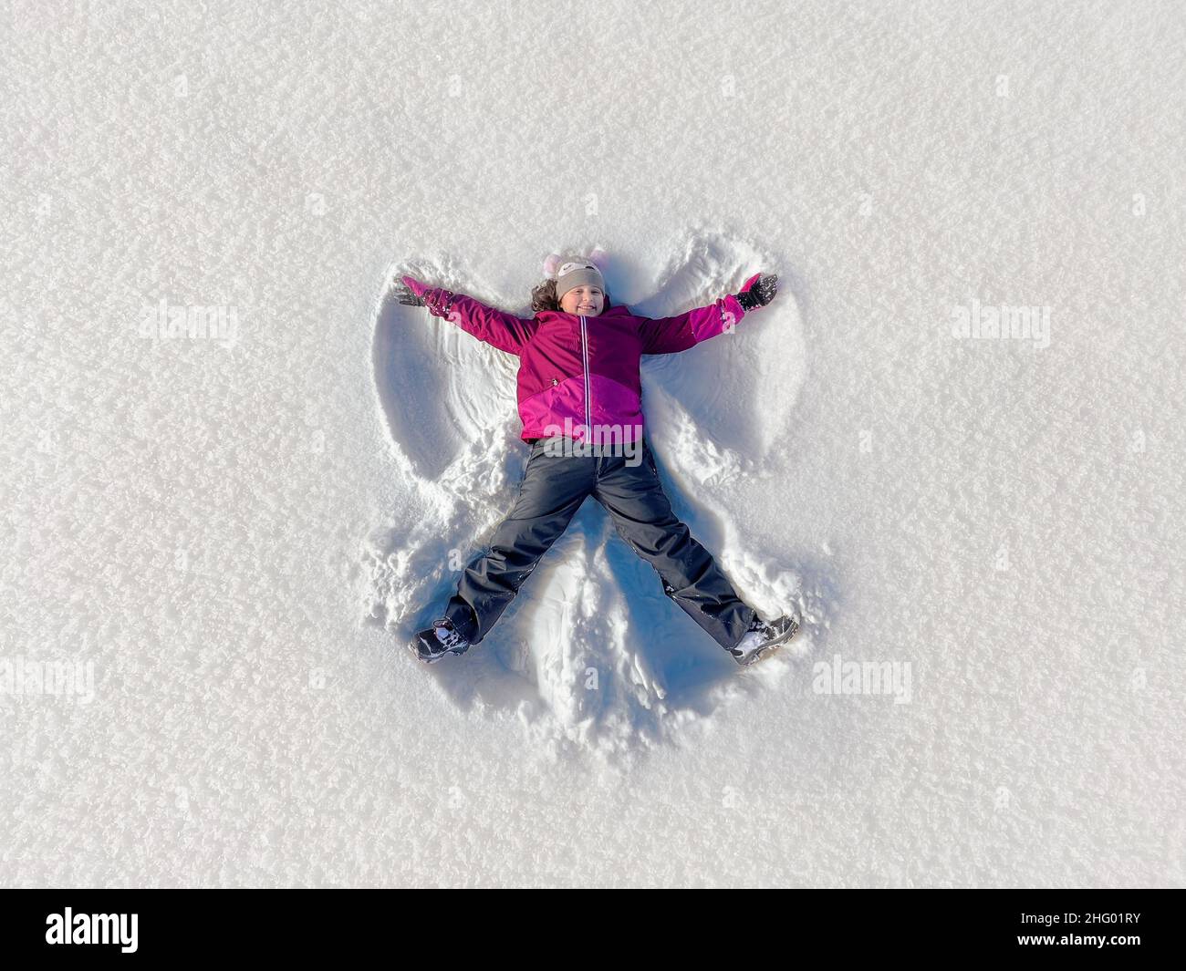 Girl making angels in the snow Stock Photo - Alamy