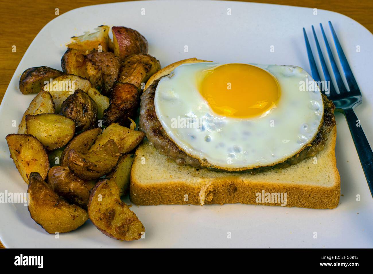 fried egg with sausage patty on toast with a side of home fries Stock ...
