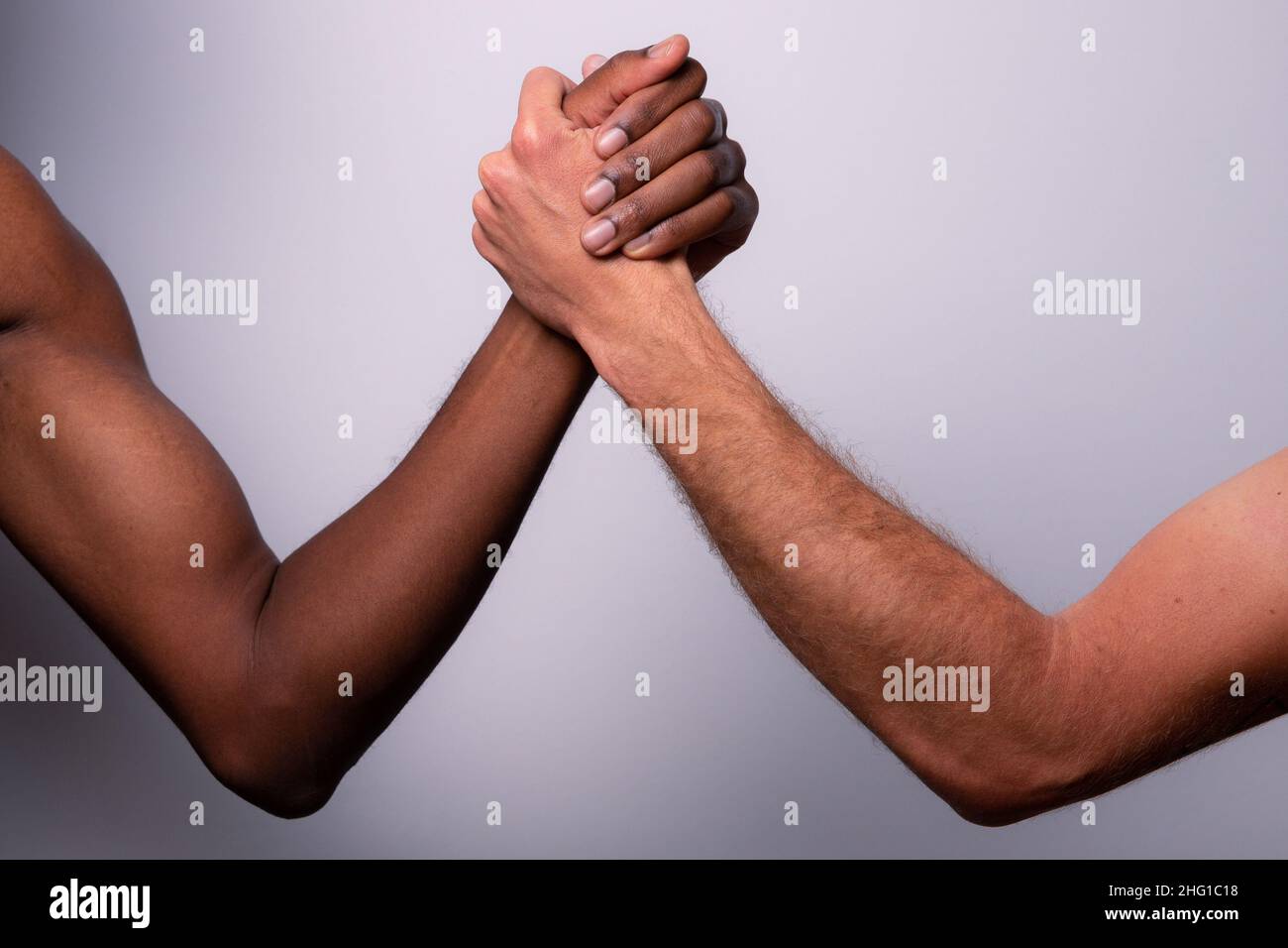 Two arms, one white caucasian and one black african, do arm wrestling ...