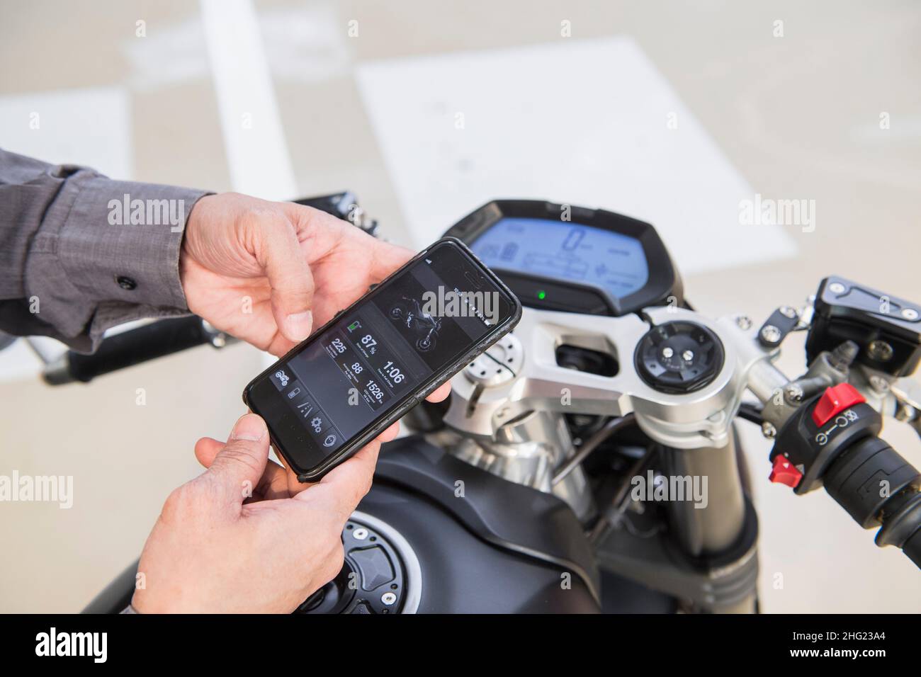 technician checking electric motorcycle with smartphone at workshop ...