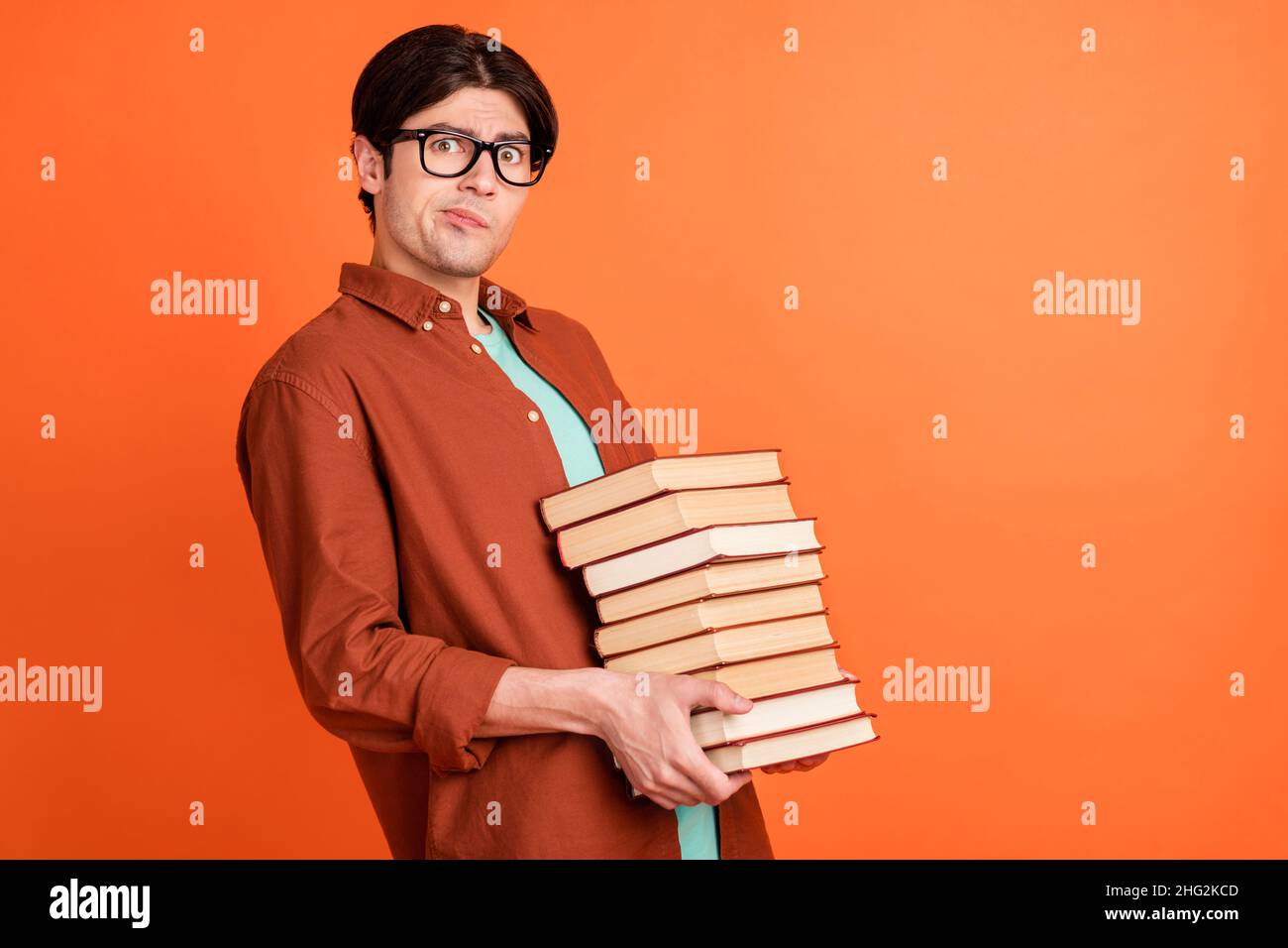 Photo of unhappy upset young college student geek nerd hold heavy stack ...