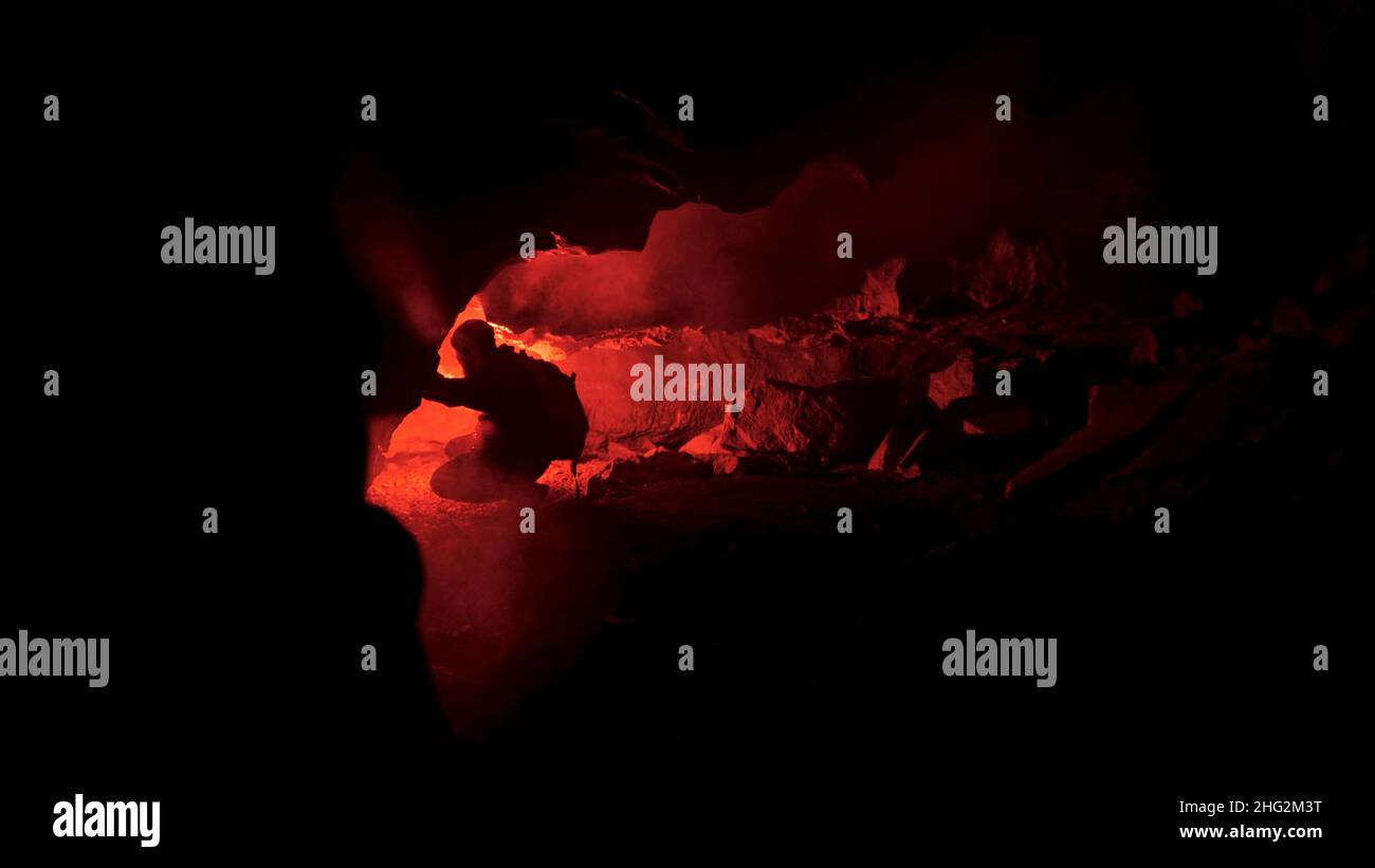 Man silhouette in an underground abandoned crypt with burning red ...