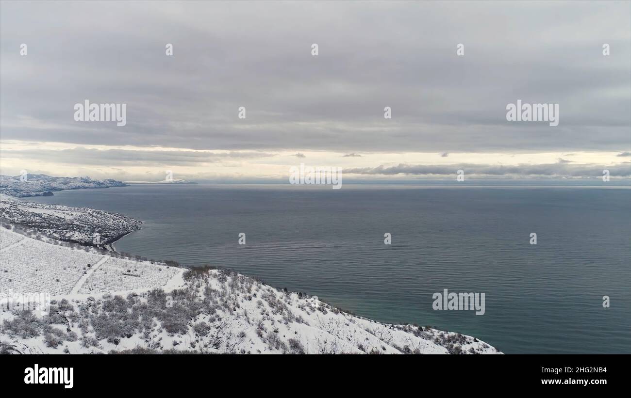 Beautiful winter seascape with snowy fields, forest and blue sea on ...