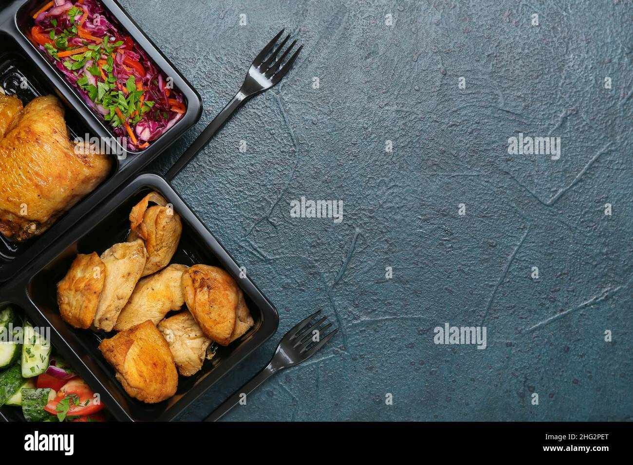 Food delivery containers with different meals and forks on dark ...