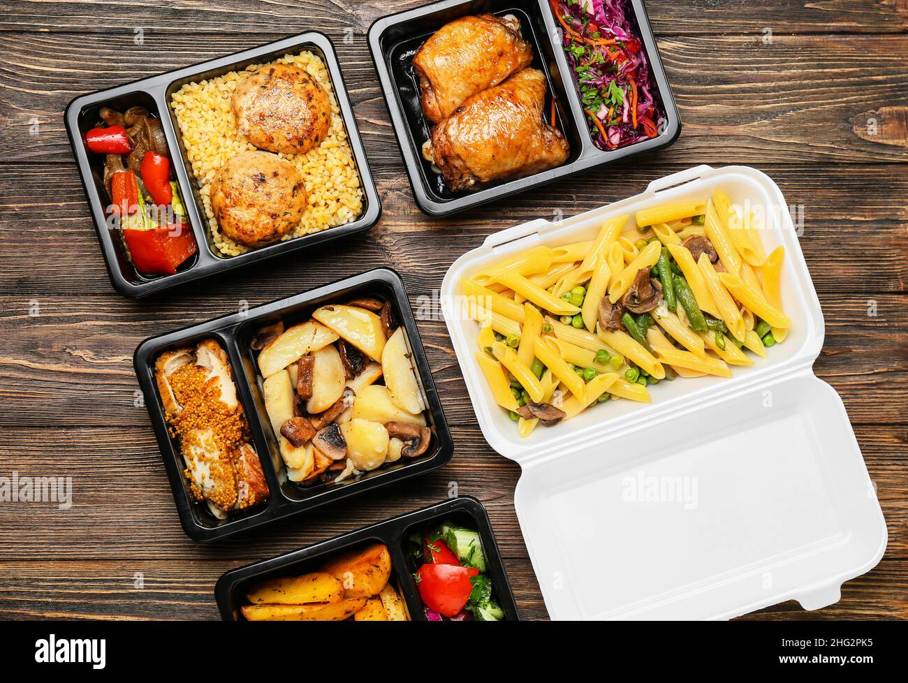 Different lunch boxes with delicious food on wooden background Stock ...