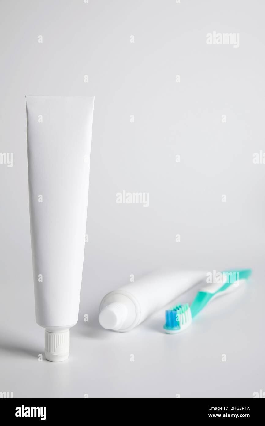Tubes with toothpaste and toothbrush on light background Stock Photo ...