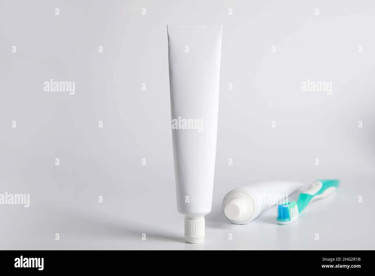 Tubes with toothpaste and toothbrush on light background Stock Photo ...