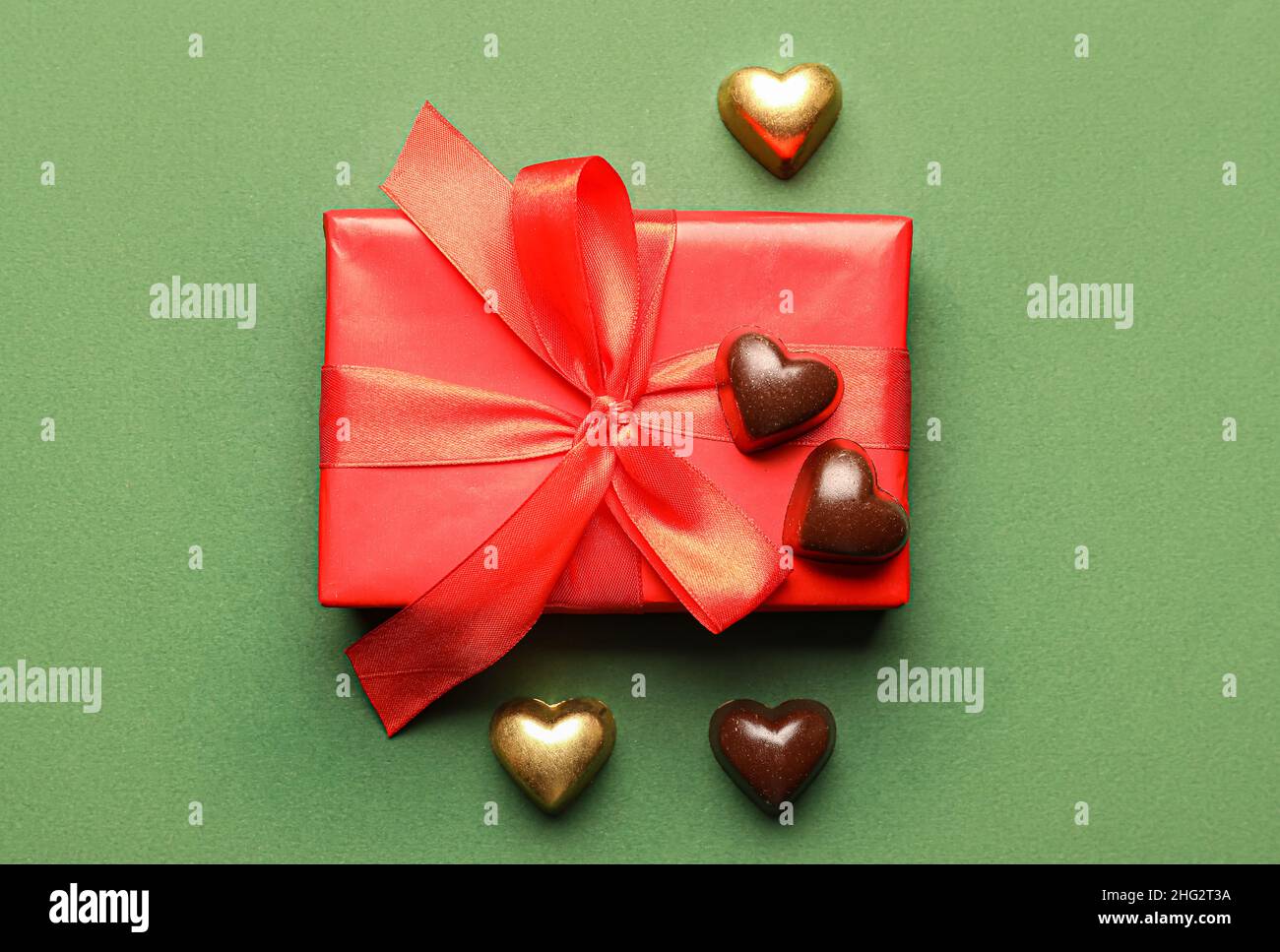 Gift with tasty heart-shaped candies on green background Stock Photo - Alamy