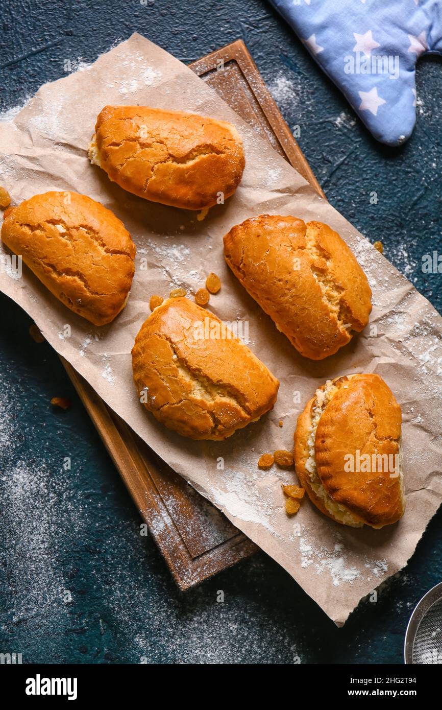Wooden board of tasty sochniki with cottage cheese on dark background ...