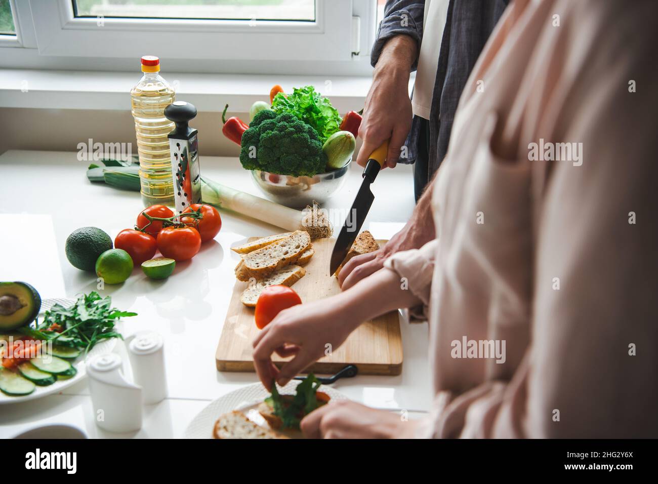 Close-up portrait of couple's hands in kitchen preparing together ...