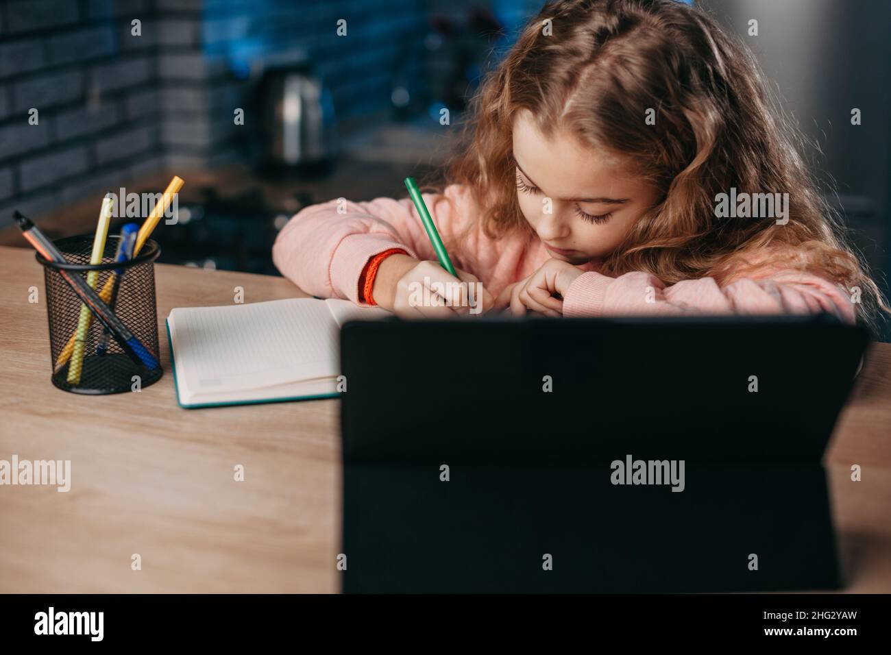 Little girl studying and taking notes using a digital tablet while ...