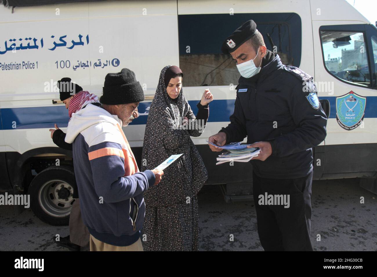 Palestinians line up around a mobile clinic with a Palestinian police ...