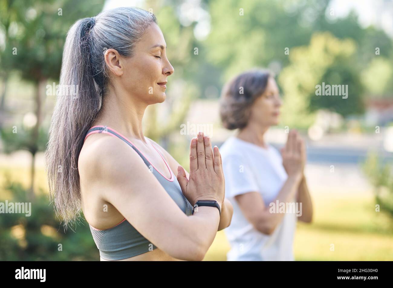 People in the park standing with hands in namaste and their eyes closed ...