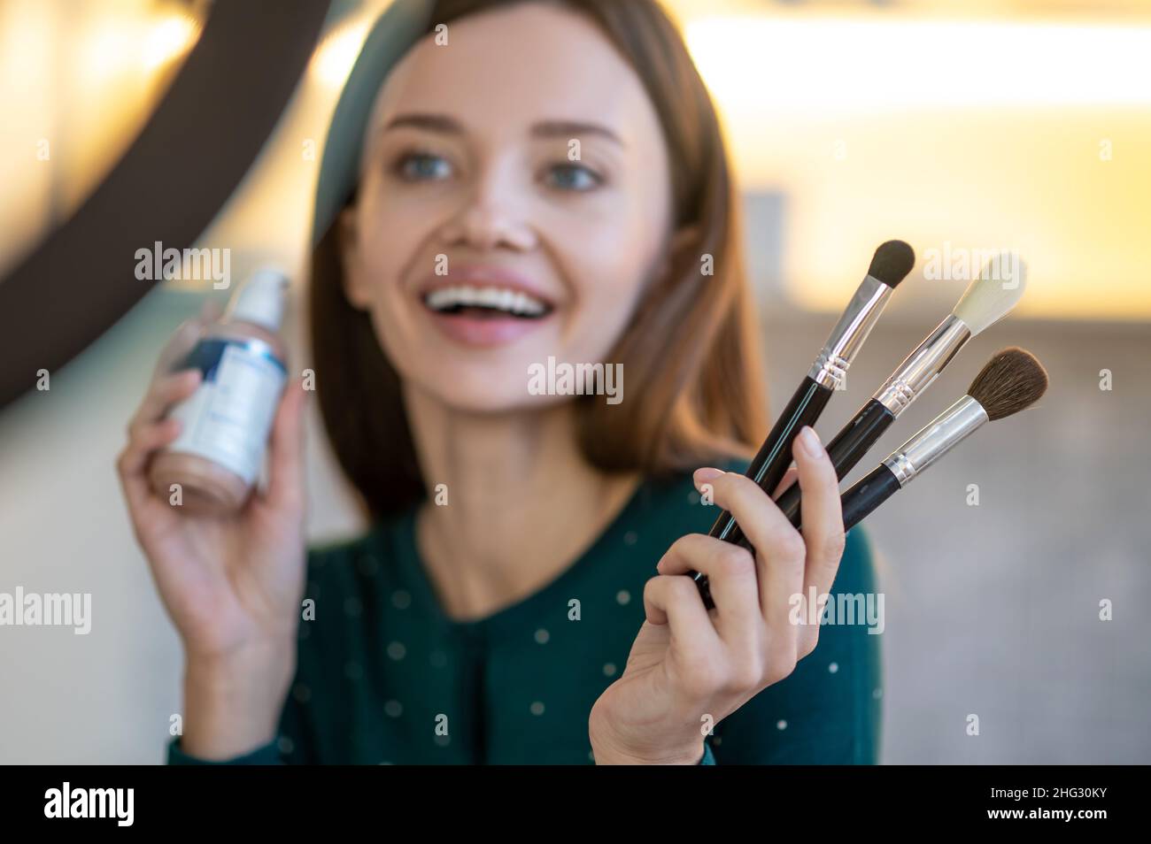 Young woman holding face brushes and smiling Stock Photo - Alamy