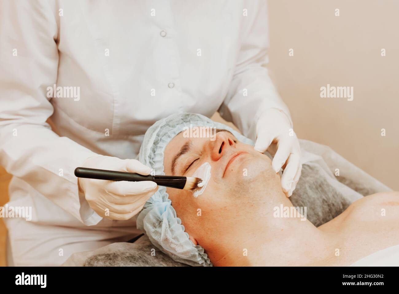 Beautician applying scrub mask on face to young man, spa beauty salon ...