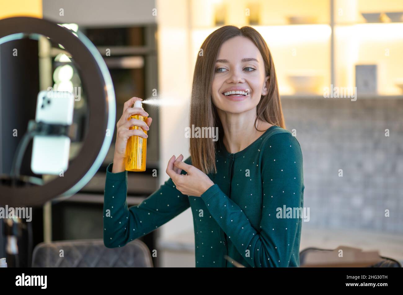 Long-haired woman spraying hairspray on her hair and smiling Stock ...