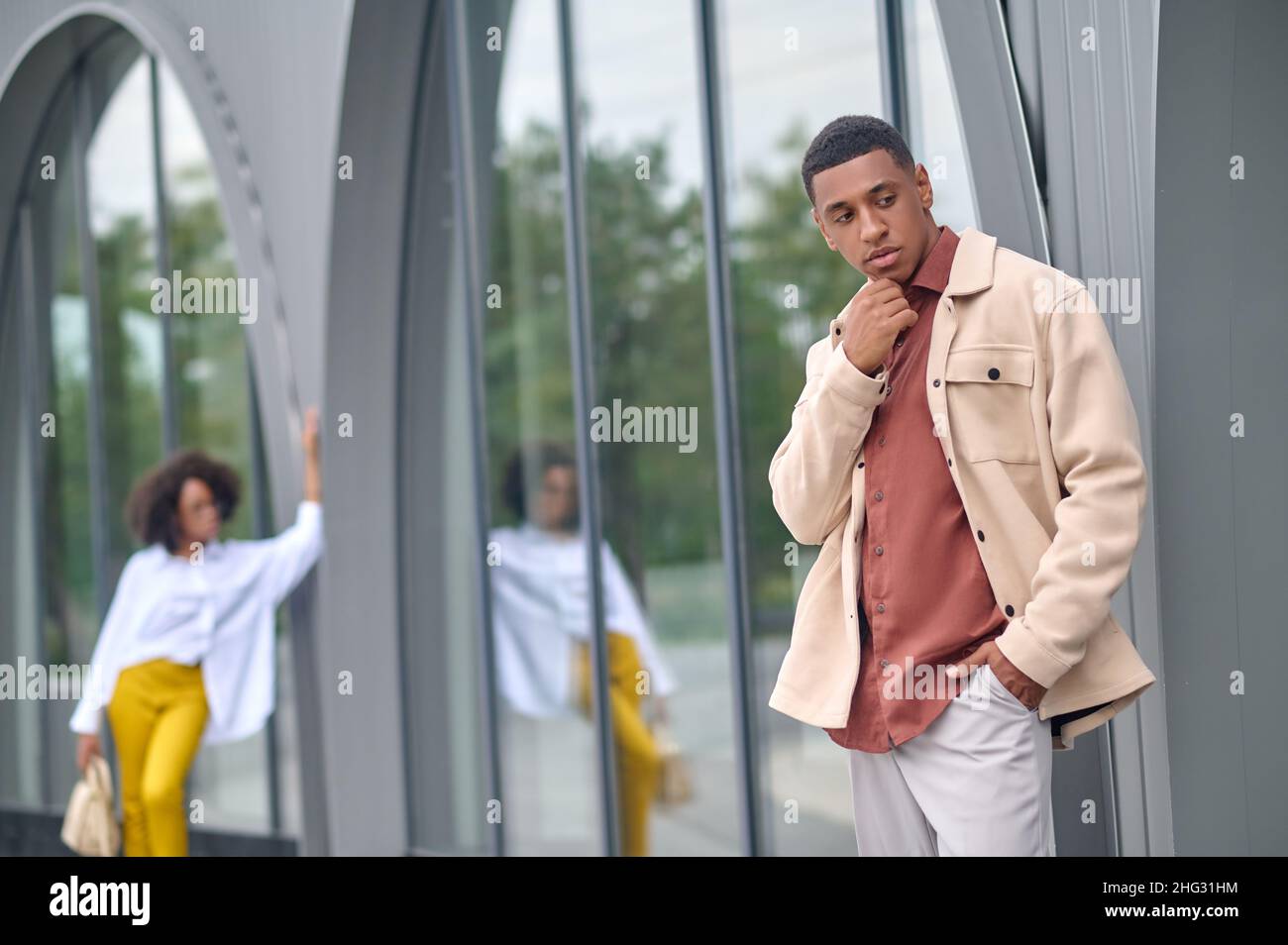Thinking man looking aside and woman standing behind Stock Photo - Alamy
