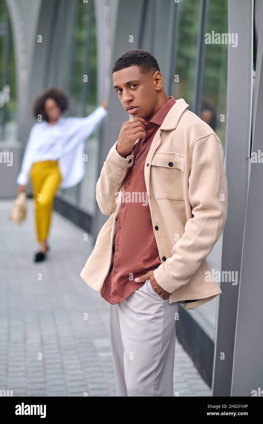 Pensive man looking at camera and woman behind Stock Photo - Alamy