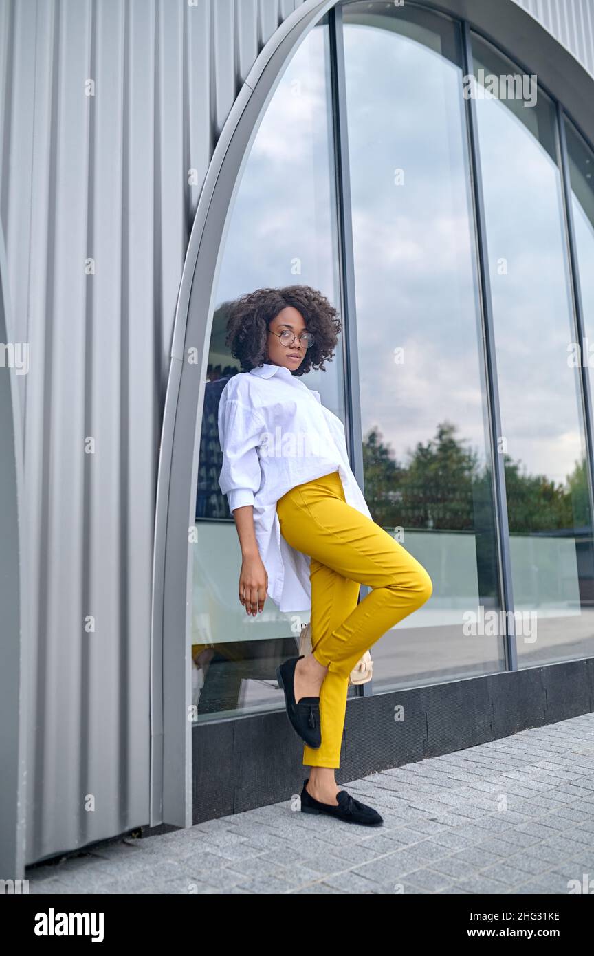 Woman standing leaning against city building Stock Photo - Alamy