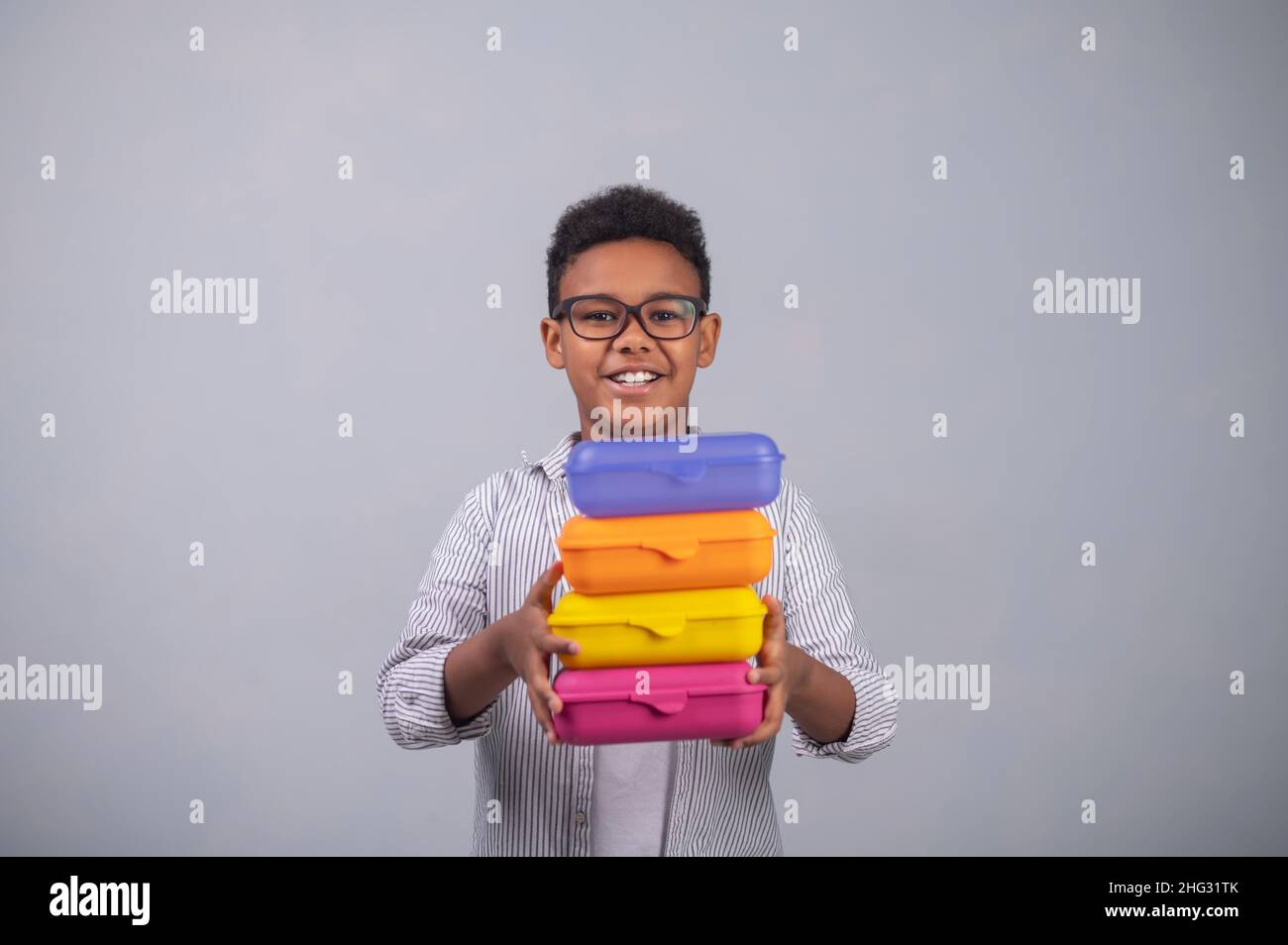 Smiling pupil demonstrating colorful plastic food containers Stock ...