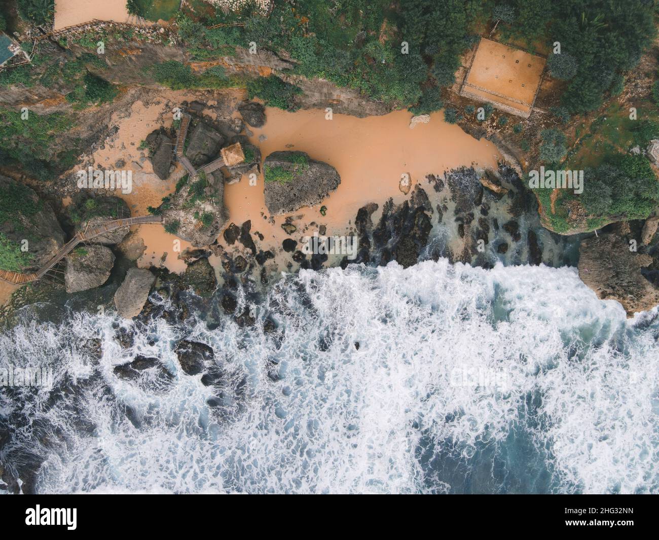 Top down aerial view of giant ocean waves crashing and foaming in coral ...