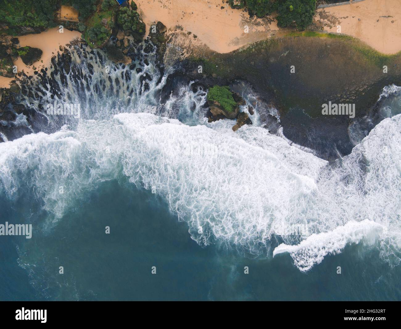 Top down aerial view of giant ocean waves crashing and foaming in coral ...