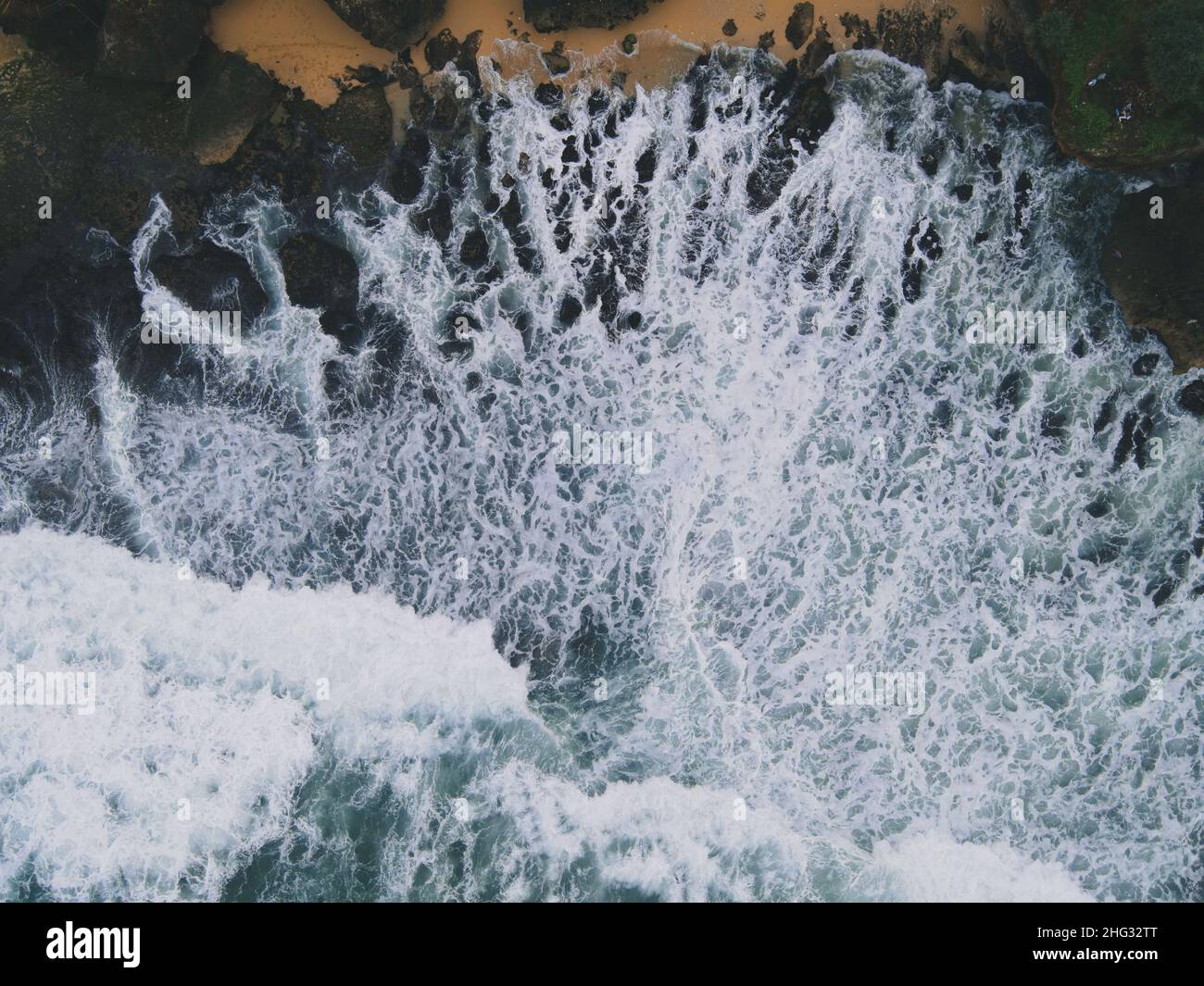 Top down aerial view of giant ocean waves crashing and foaming in coral ...