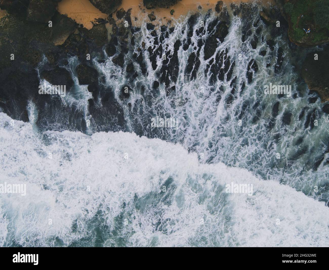 Top down aerial view of giant ocean waves crashing and foaming in coral ...