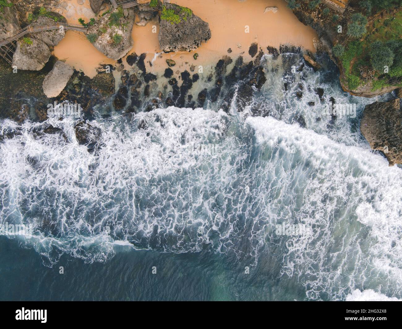 Top down aerial view of giant ocean waves crashing and foaming in coral ...