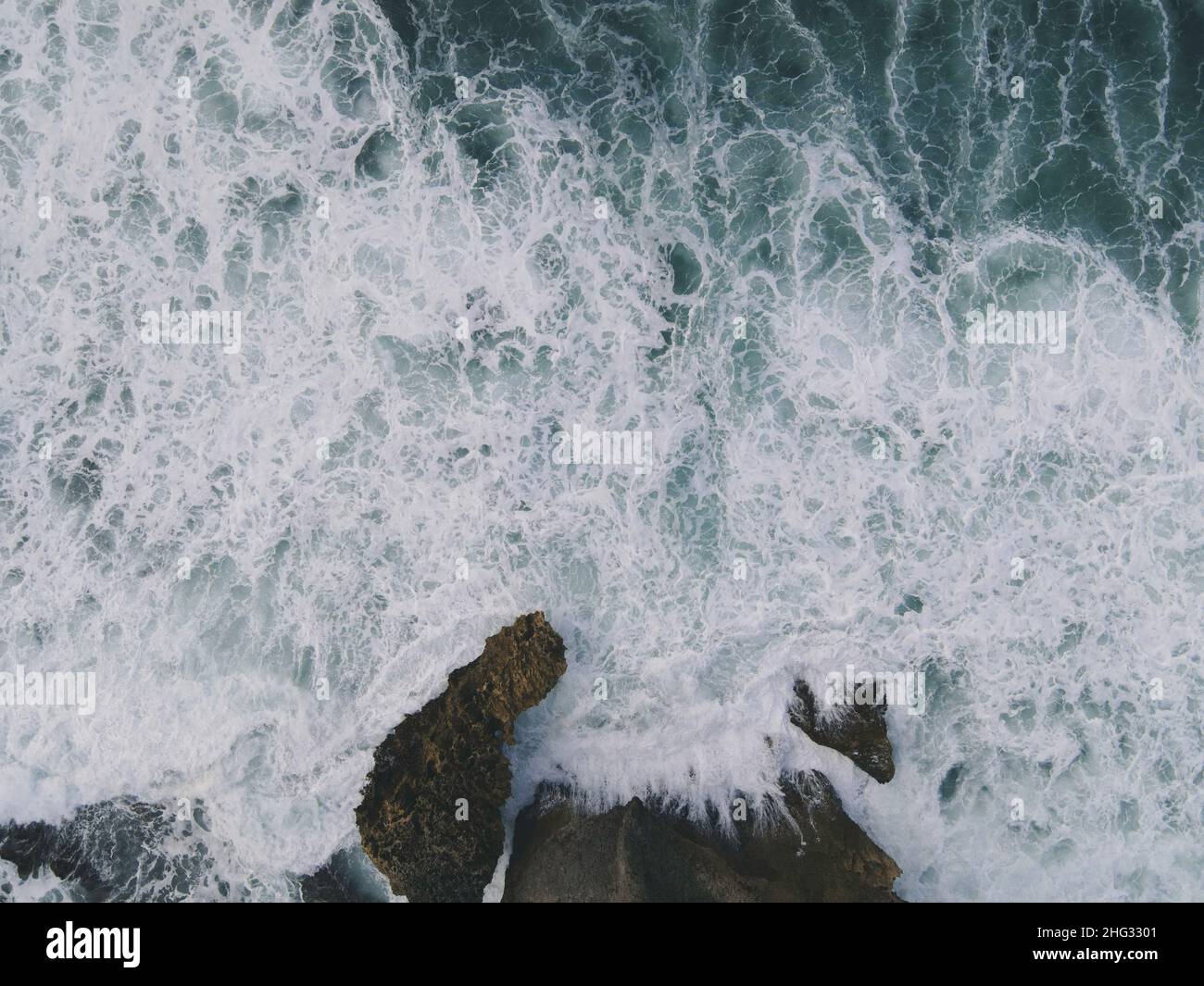 Top down aerial view of giant ocean waves crashing and foaming in coral ...