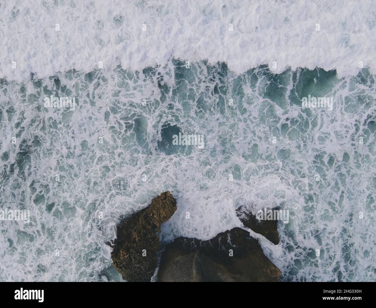 Top down aerial view of giant ocean waves crashing and foaming in coral ...