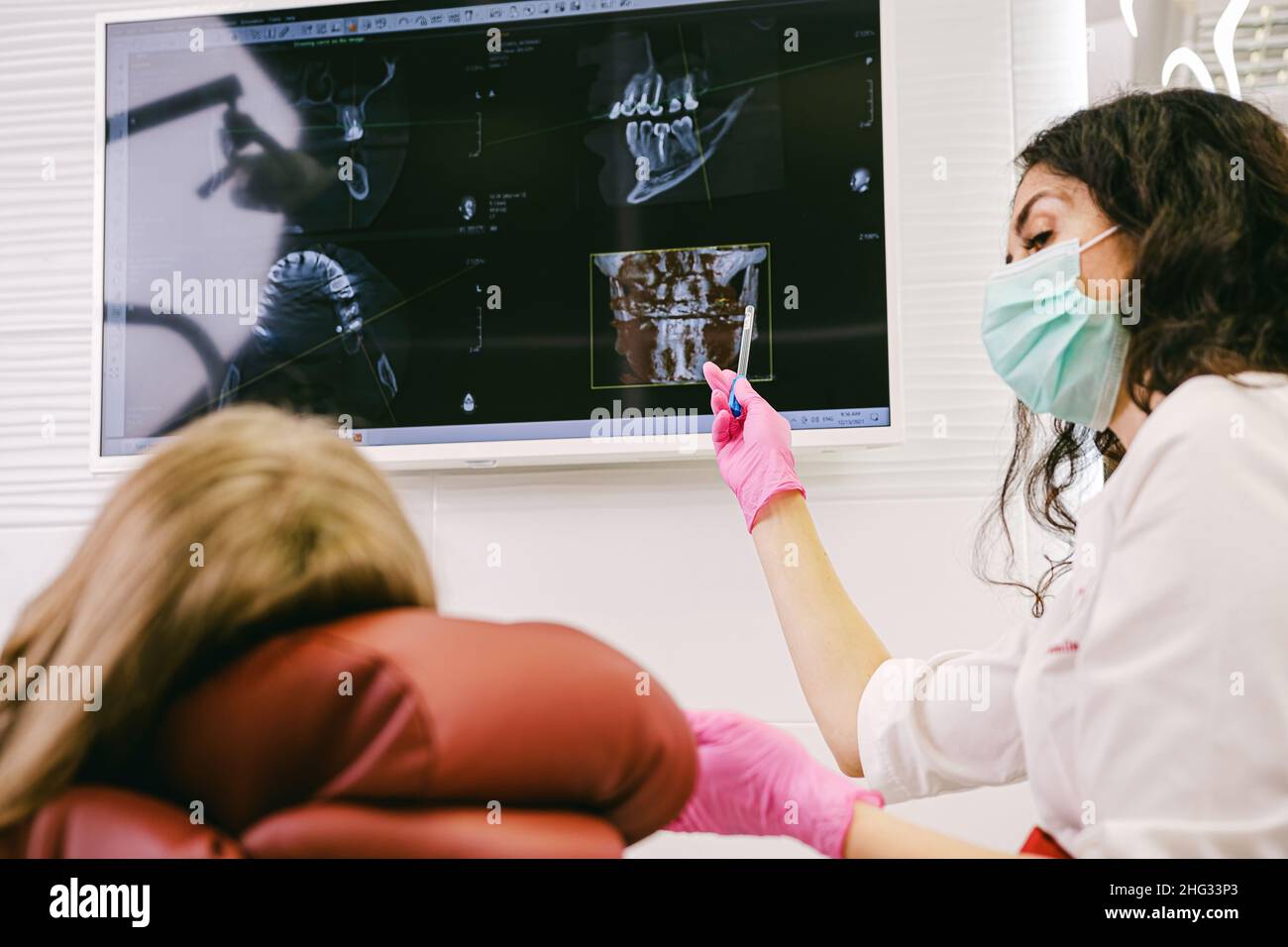 Side view photo of a stomatologist woman brunette in medical mask and ...