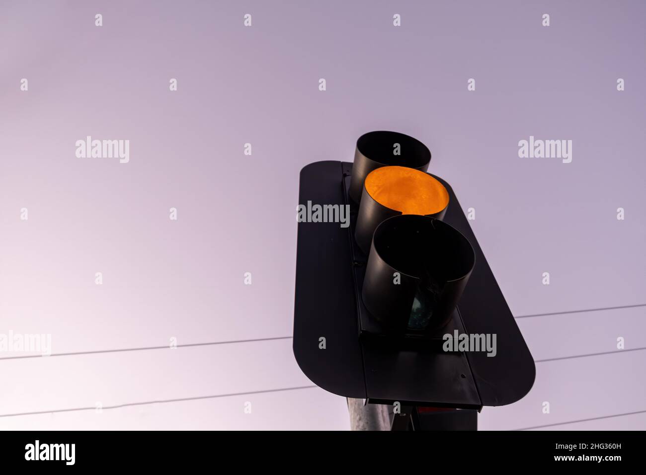 Looking up at orange traffic light against the sky at sunset with copy ...