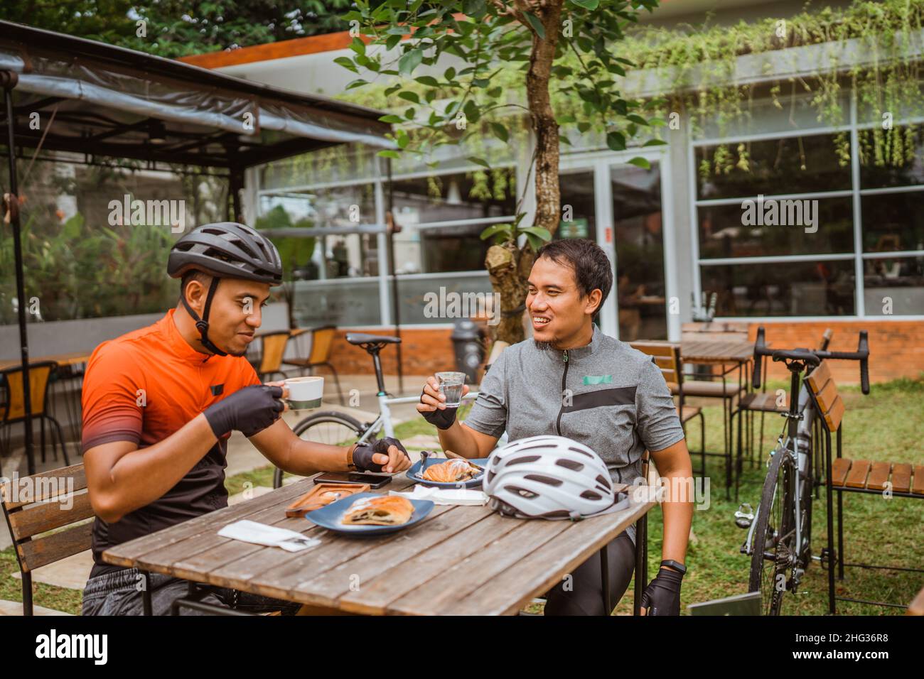 two cyclist enjoying coffee in the cafe after riding Stock Photo - Alamy