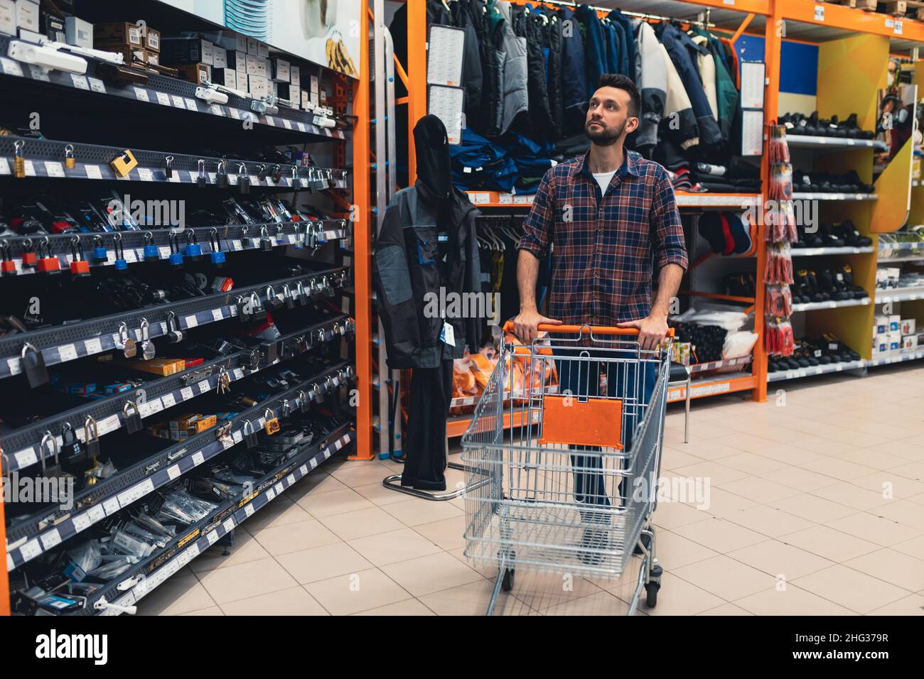 a customer with a cart in a hardware store chooses a padlock for a gate ...