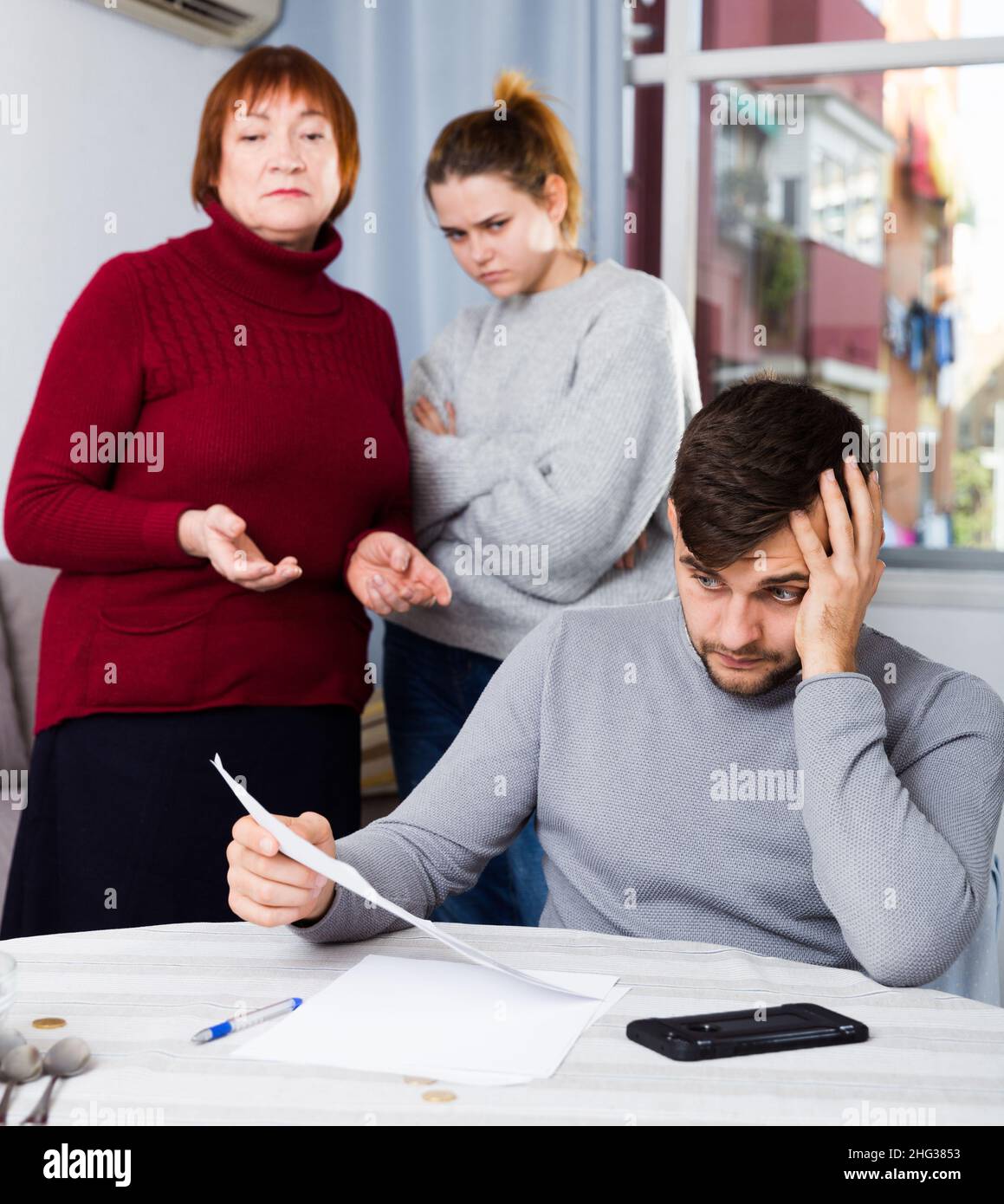 Frustrated man with papers on background with discontented family Stock ...