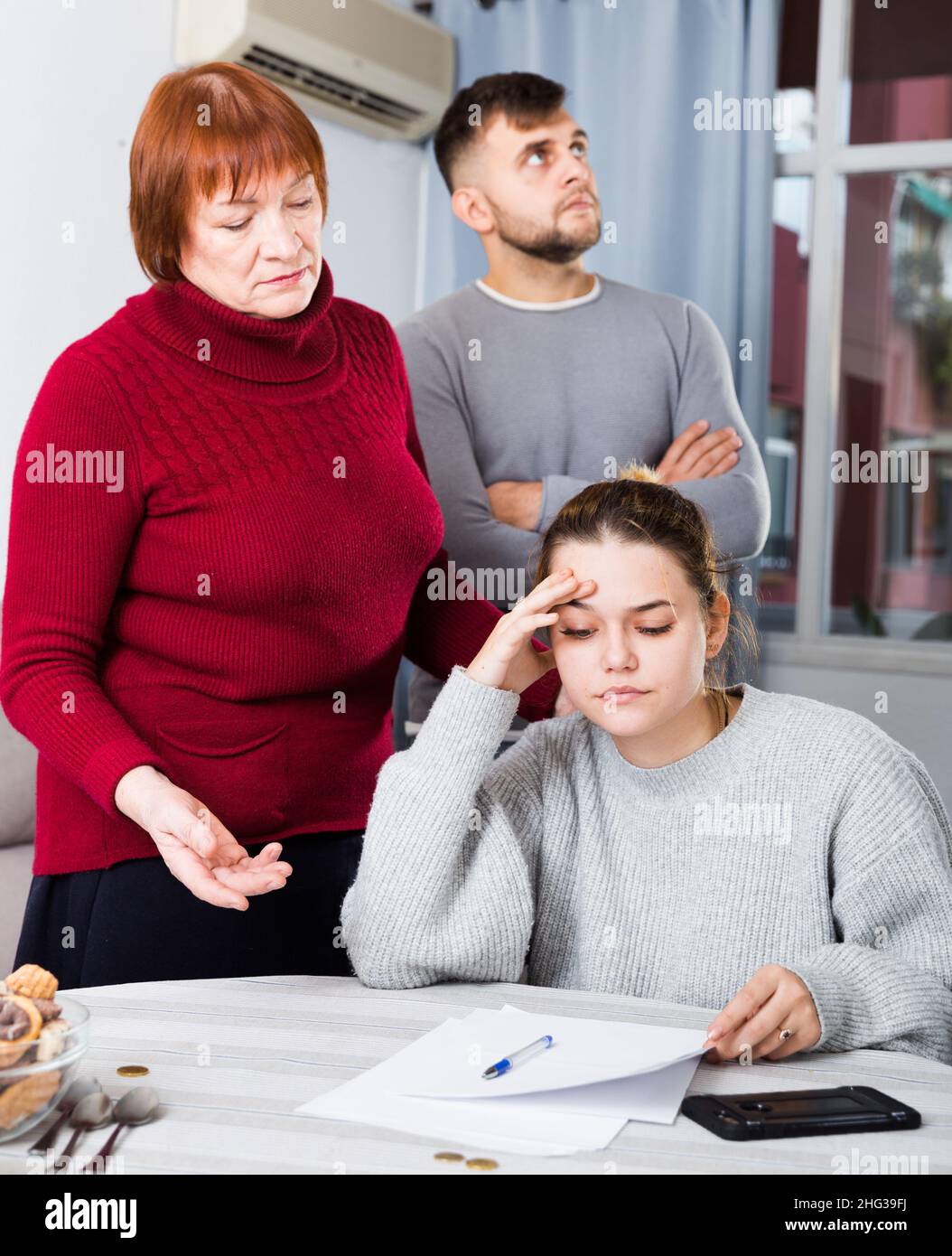 Distressed girl with paperwork and irritated family behind Stock Photo ...
