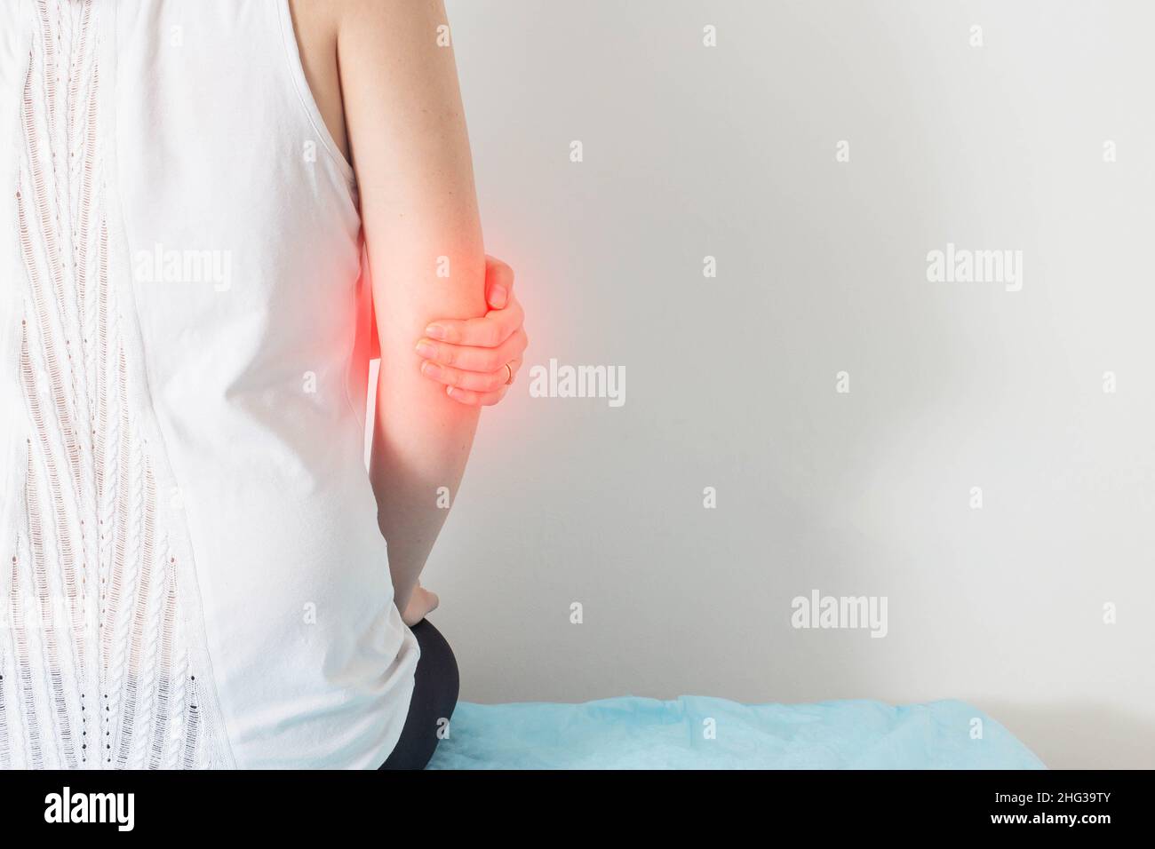 The girl holds on to the sore elbow on which there is pain and redness ...