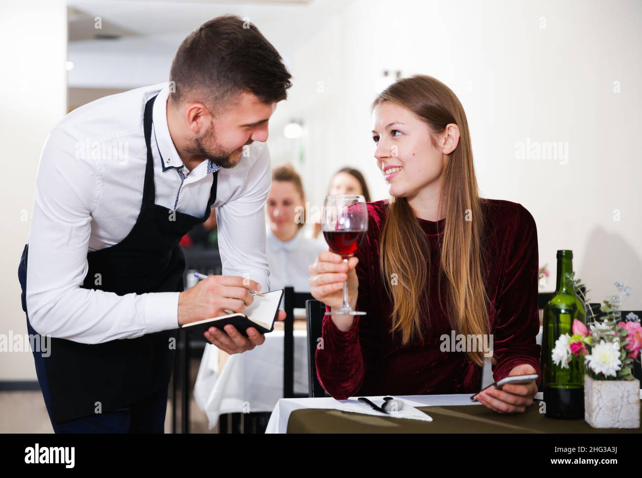 Waiter is taking order from young female in restaurante Stock Photo - Alamy