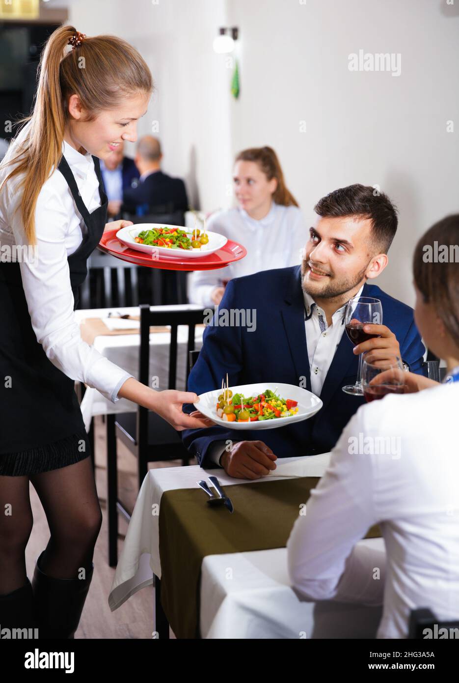 Woman waiter is giving dish to client in restaurante Stock Photo - Alamy