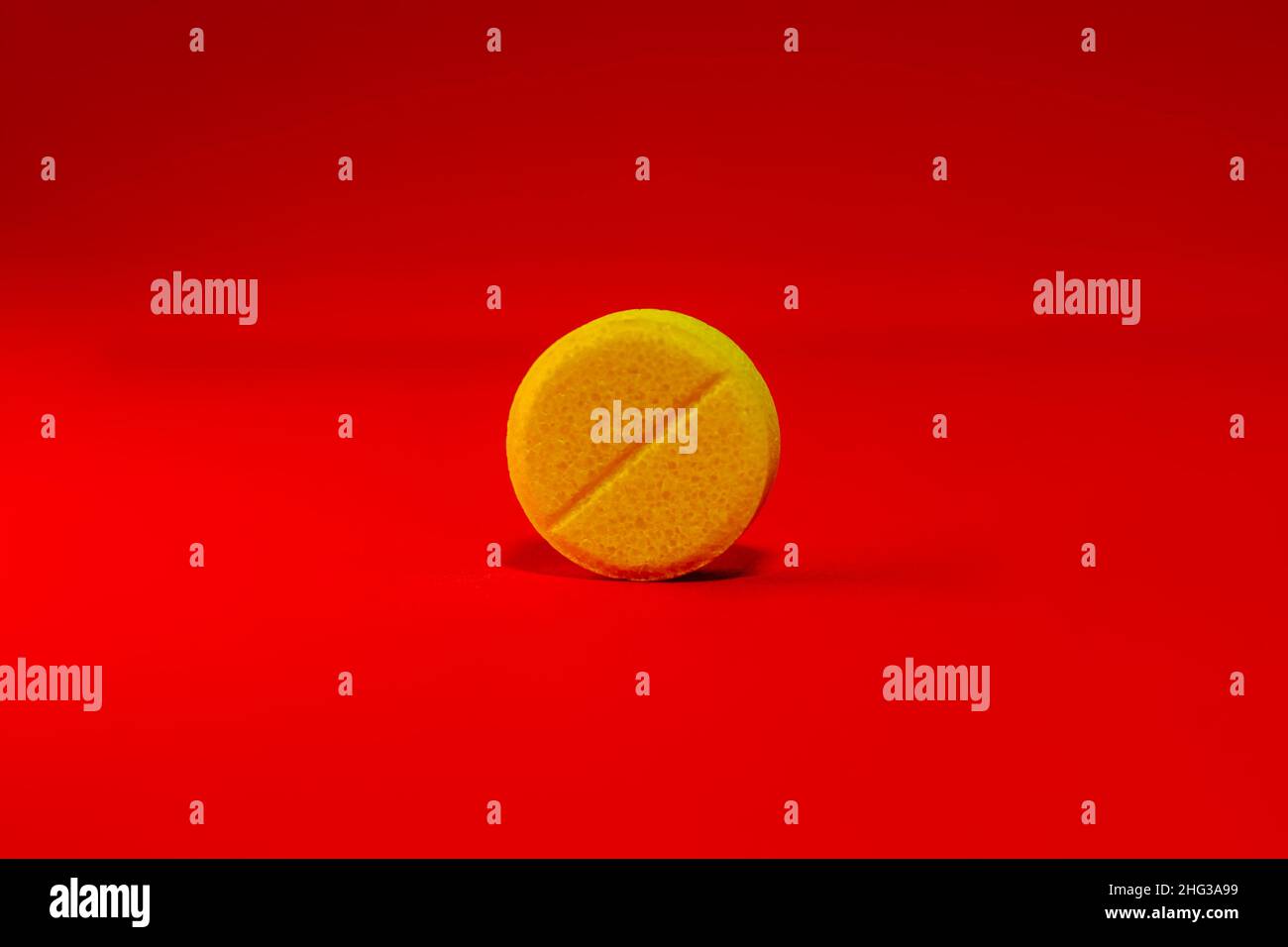 Yellow one pill on a bright red background close-up. Place for your ...