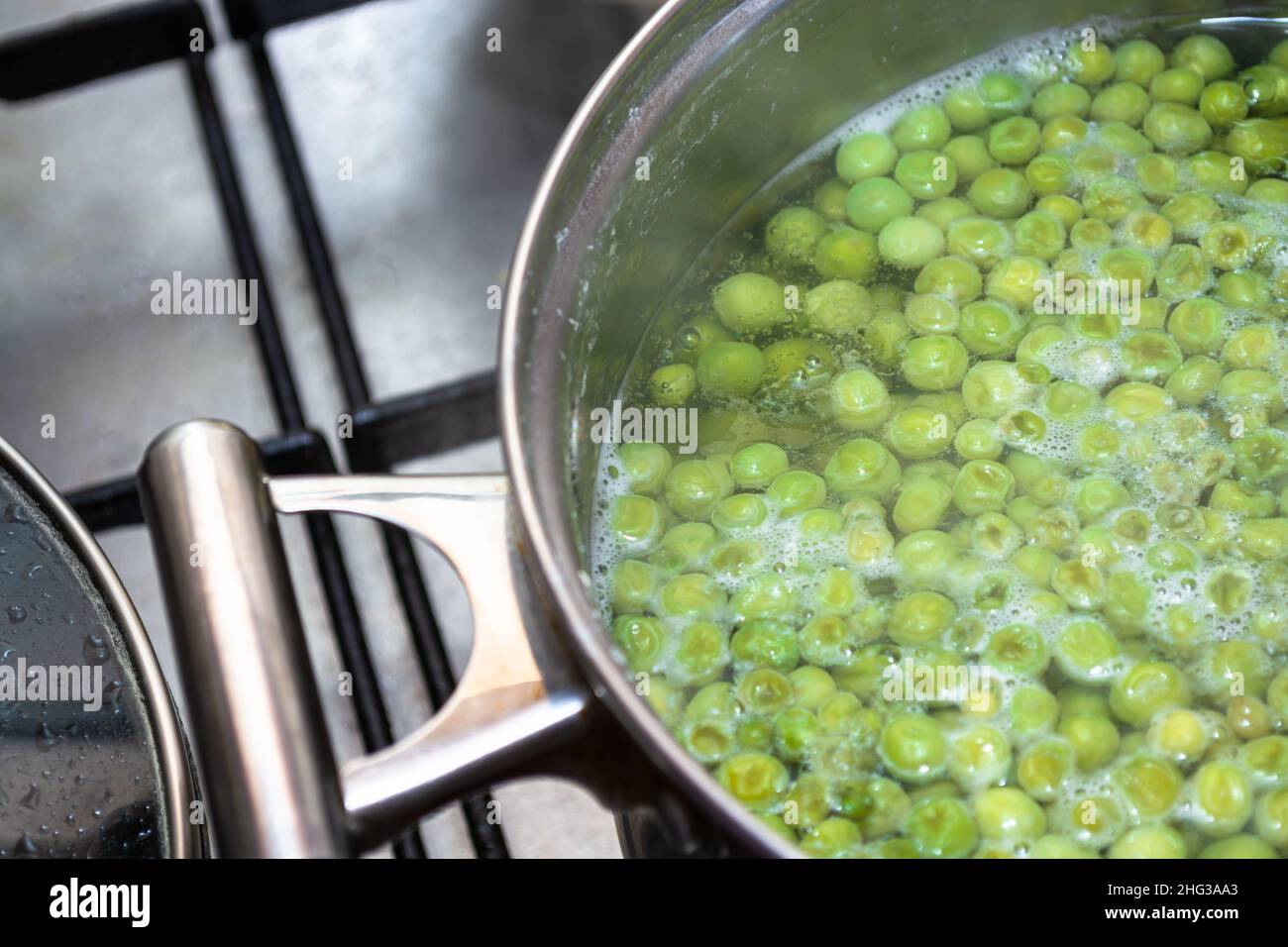 Cooking green peas in a metal pot on a gas stove. Boiling. Culinary ...