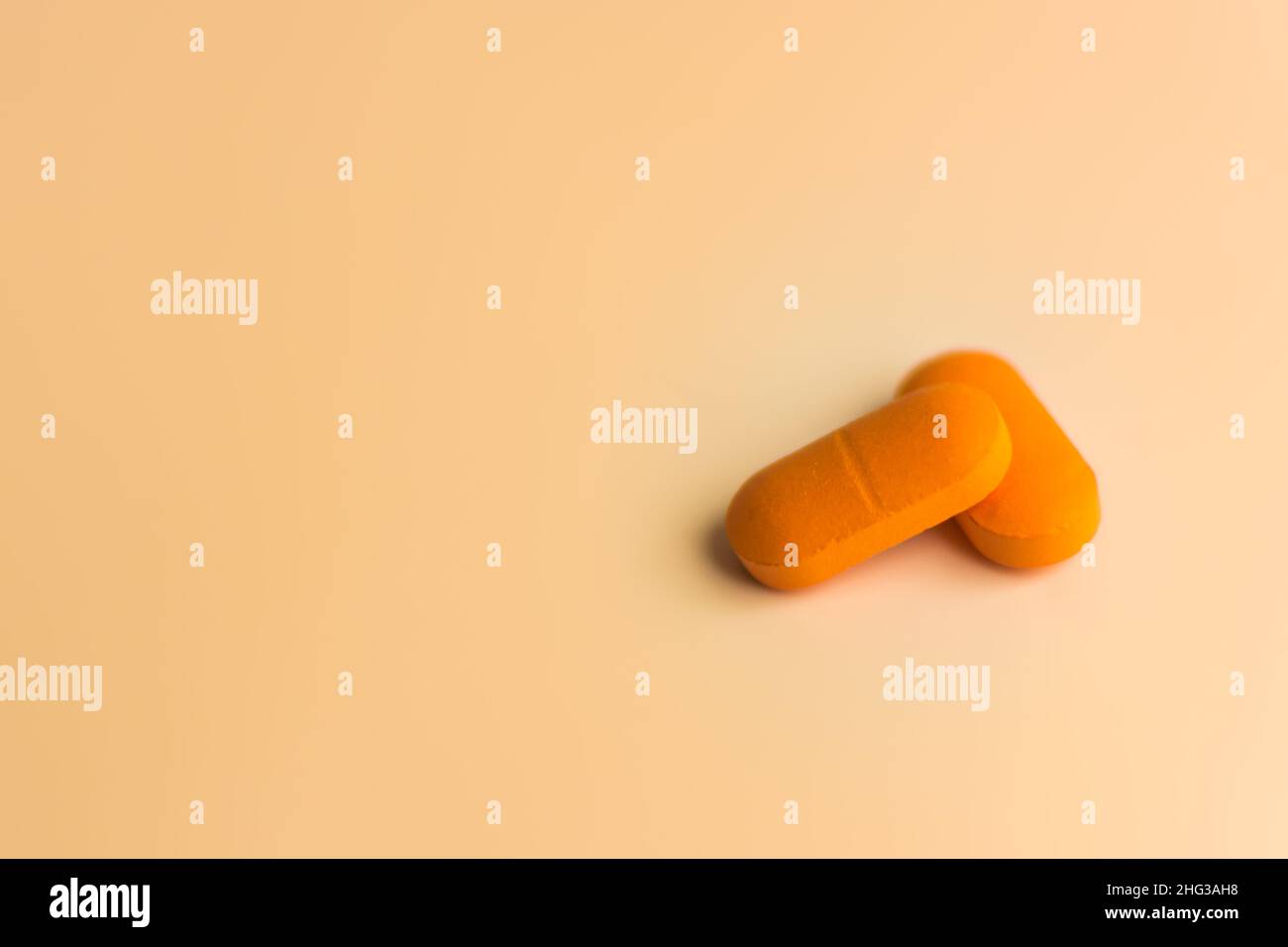 Two large orange pills on a gentle orange background. Selective focus ...