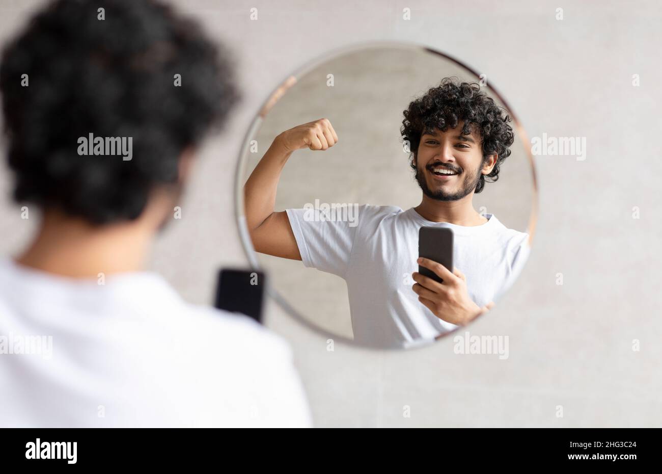 Excited indian man taking photo on smartphone in bathroom mirror ...