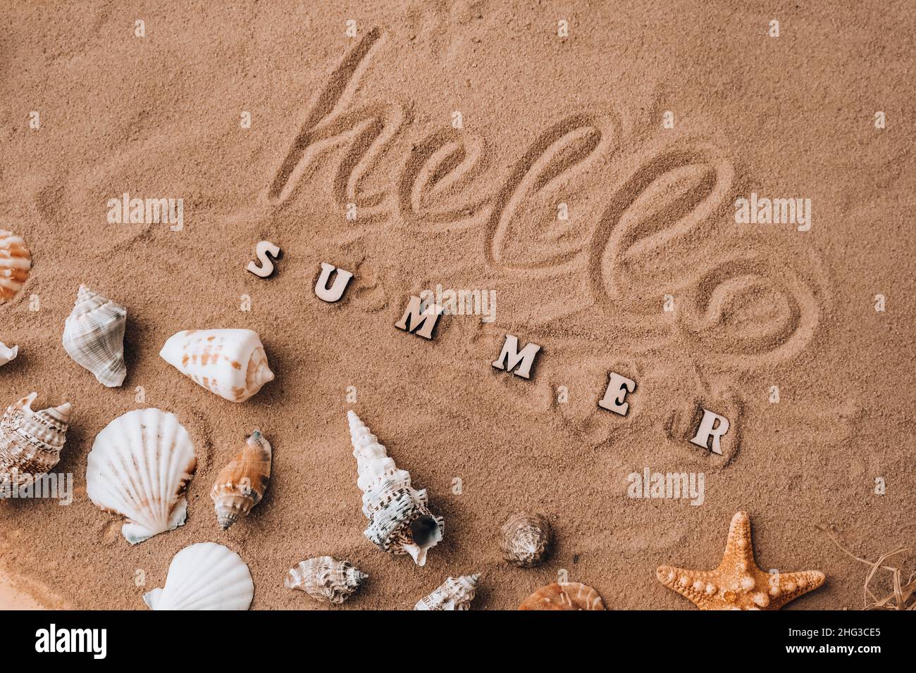 Composition with text HELLO SUMMER seashells, pebbles, mockup on sand ...