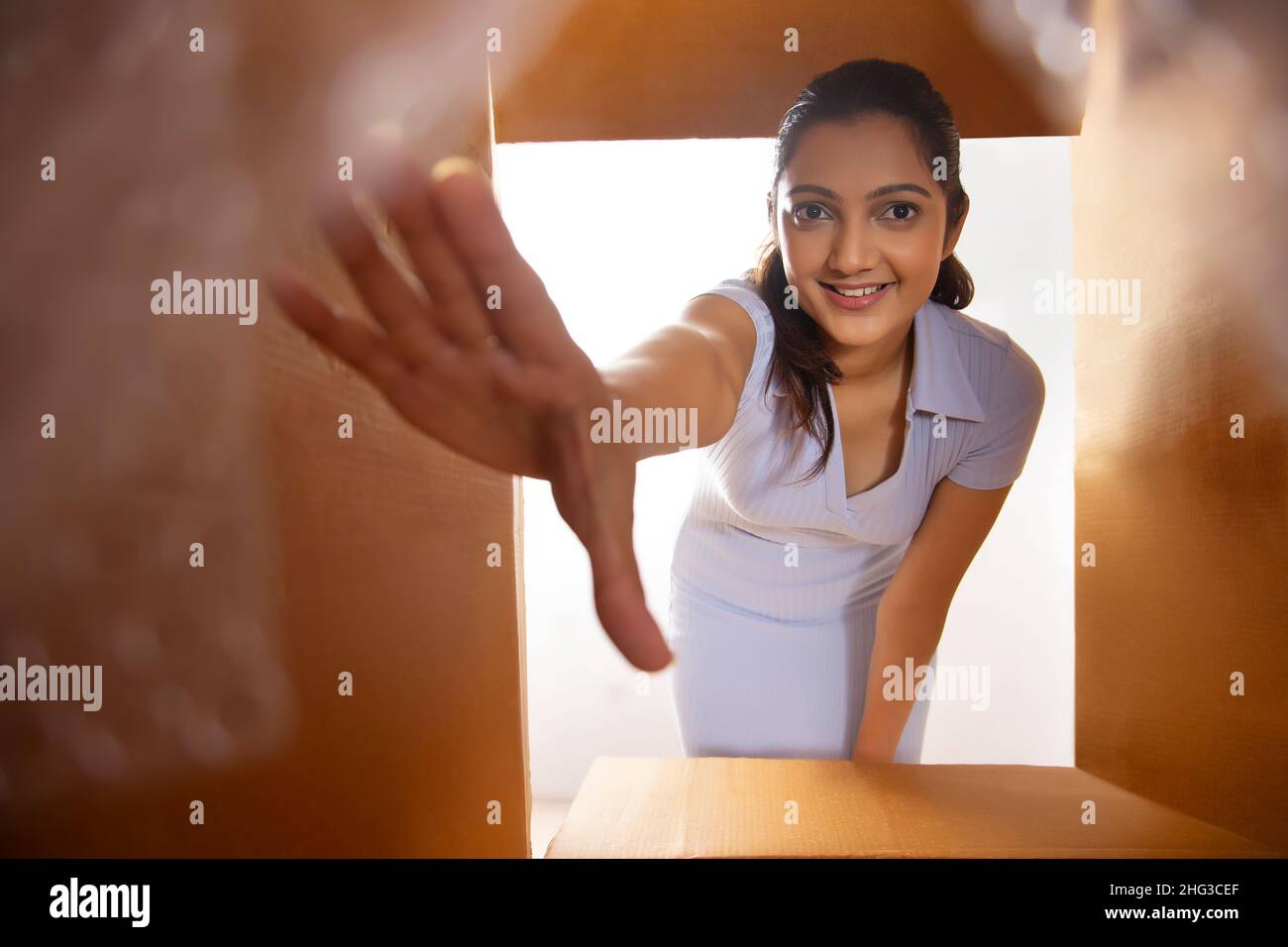 Adult girl raising her hand through cardboard boxes Stock Photo - Alamy