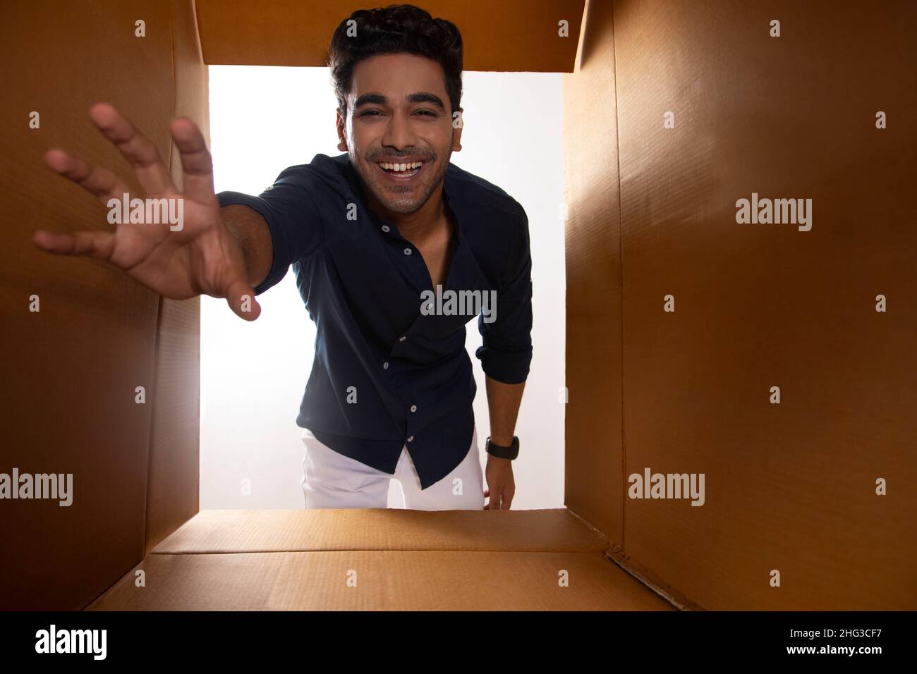 Adult boy raising his hand through cardboard boxes Stock Photo - Alamy