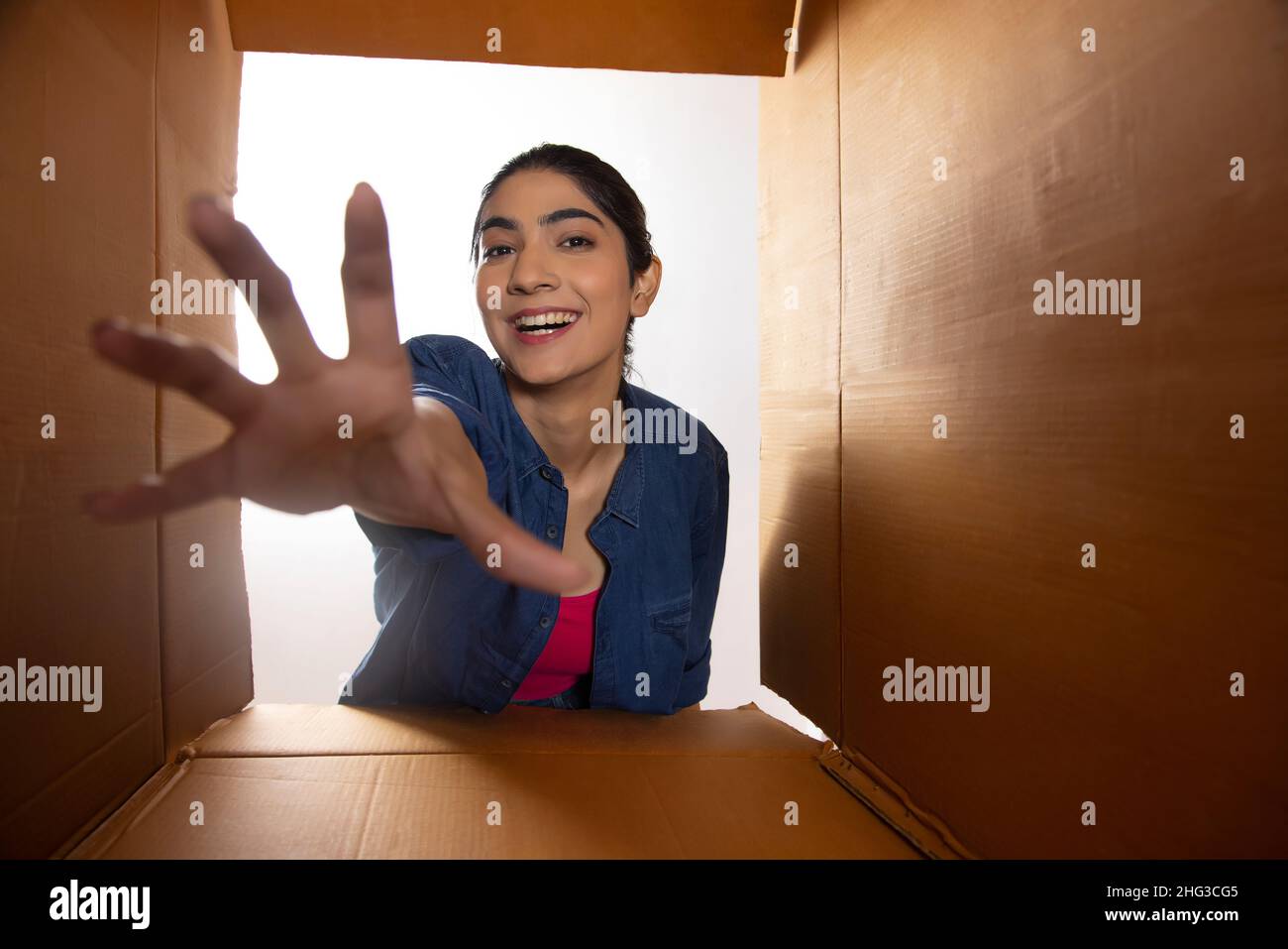 Adult girl raising her hand through cardboard boxes Stock Photo - Alamy